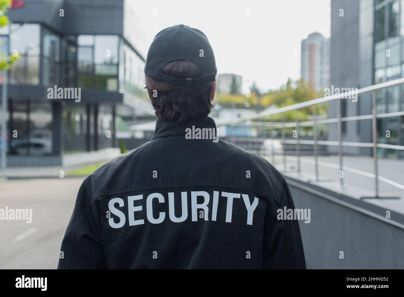 back view of guard in uniform with security lettering standing on city ...