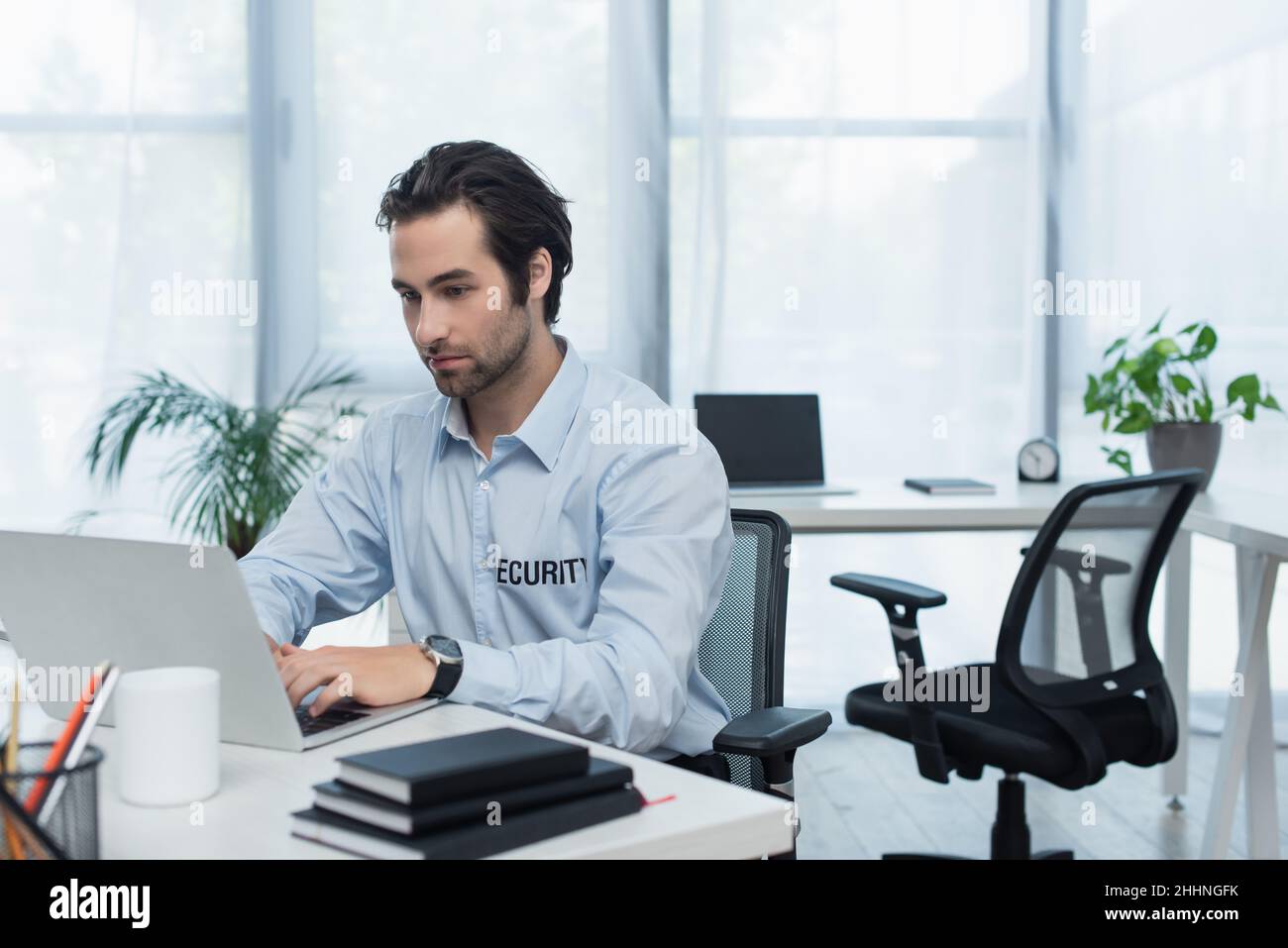 young security man typing on laptop in supervision room Stock Photo - Alamy