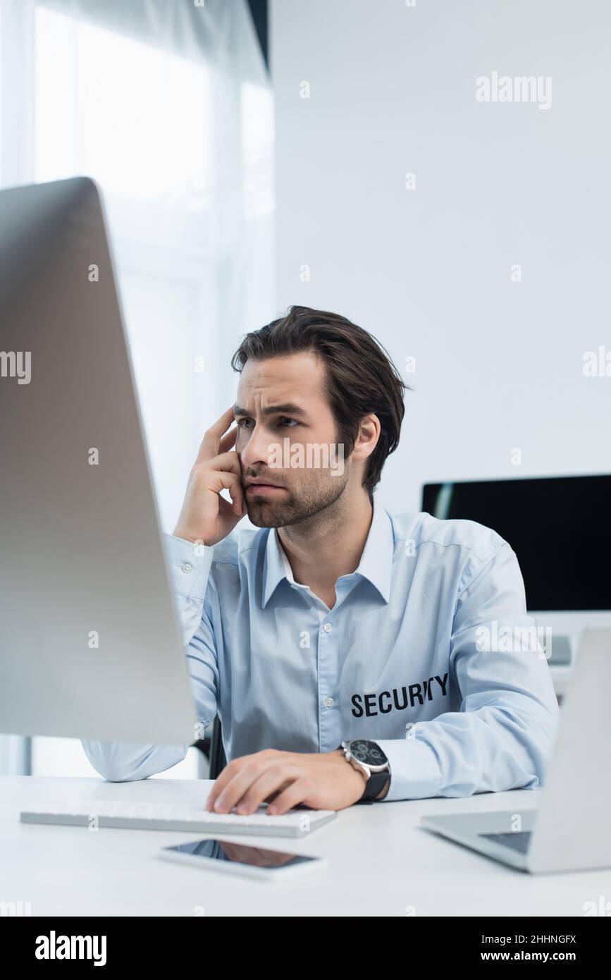 serious security man looking at blurred computer monitor in ...