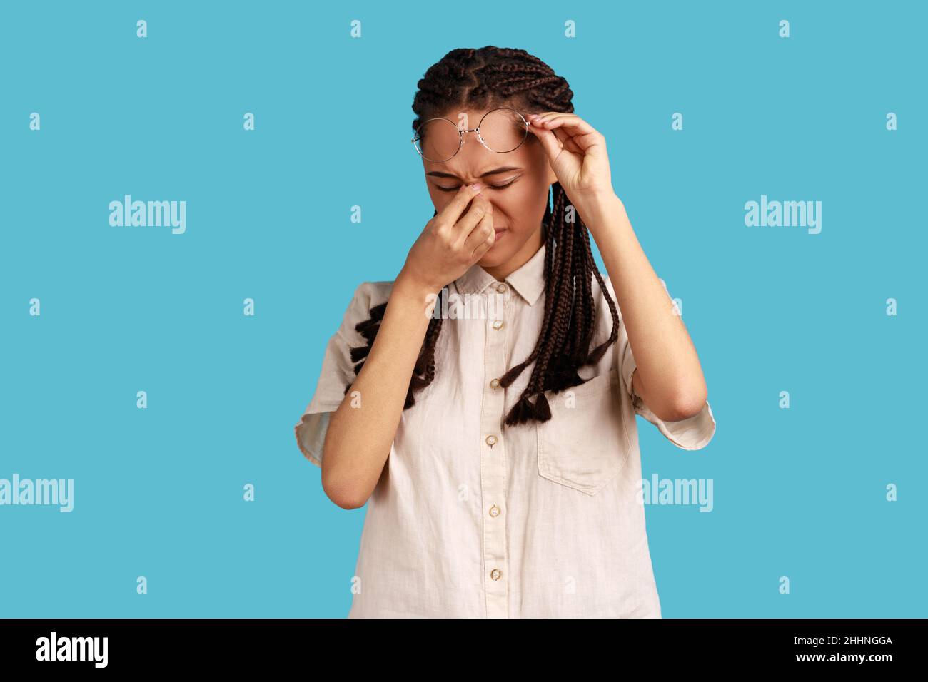 Portrait of frustrated woman with black dreadlocks touching closed eyes ...