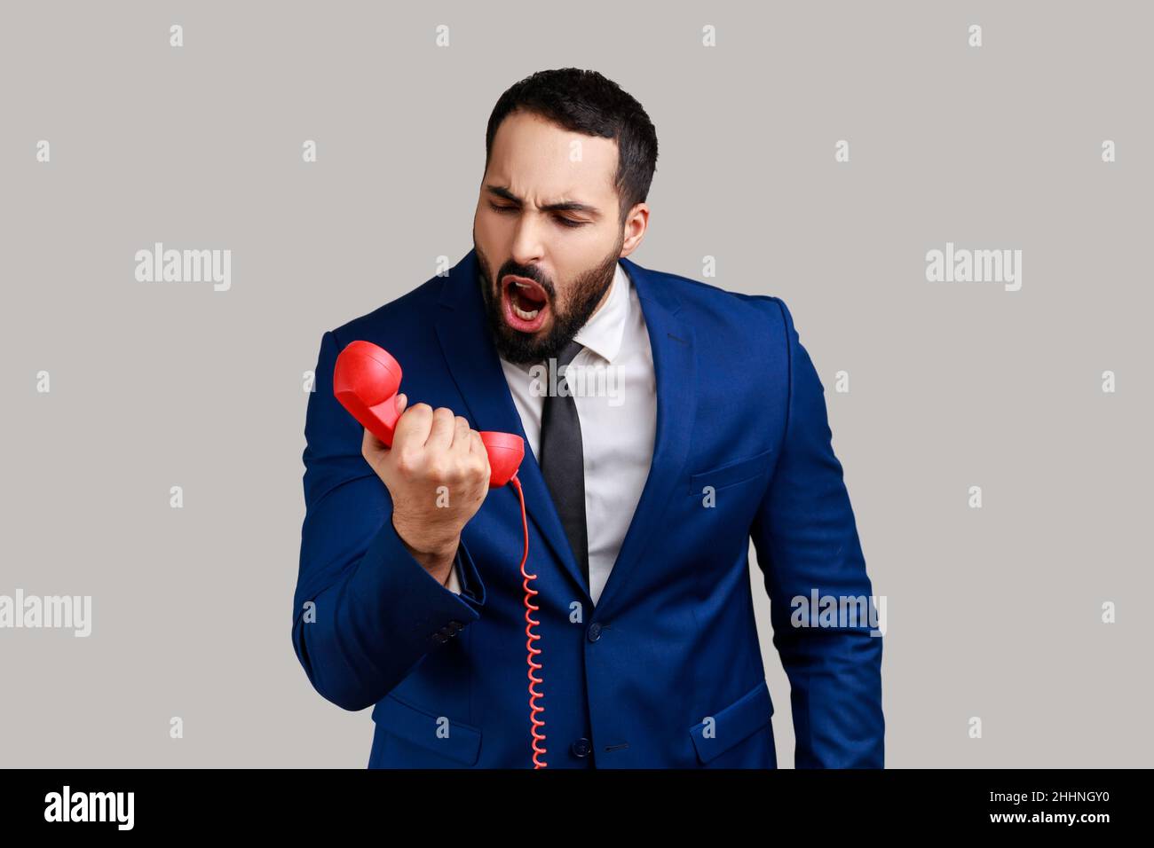 Bearded man screaming into phone handset, annoyed by telephone ...
