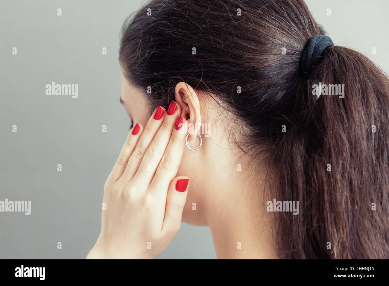 A young caucasian woman closes her ear with her fingers with a red ...