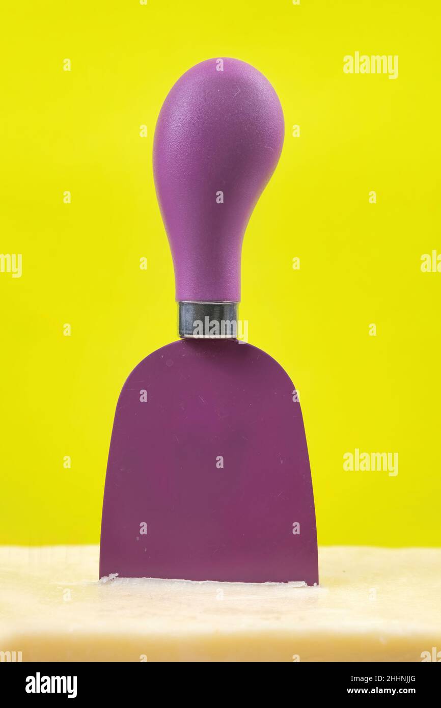 Purple cheese knife over yellow background Stock Photo - Alamy
