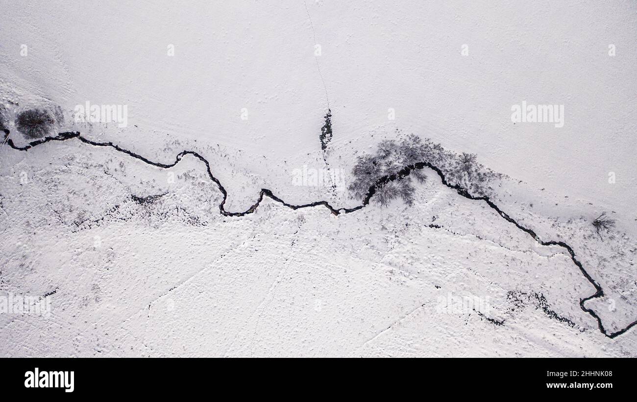 Aerial view of a thin river on a white snowy field Stock Photo - Alamy