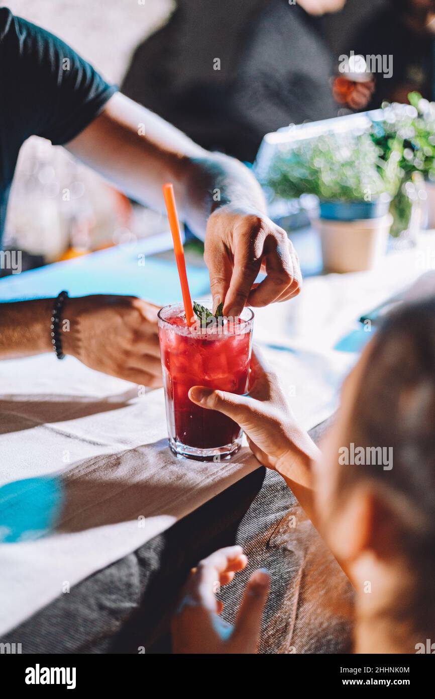 Vertical shot of a red drink with glasses in a girl's hand being ...