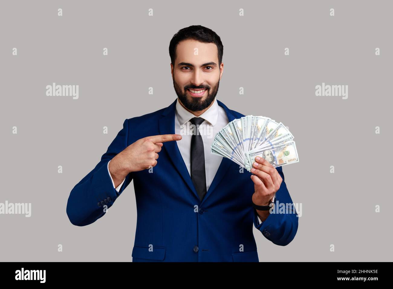 Rich bearded man pointing at dollar banknotes and looking with happy ...