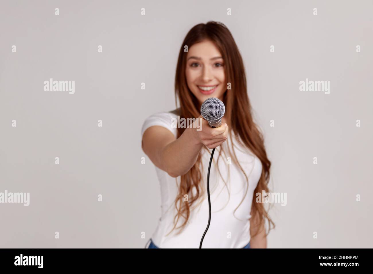 Portrait of smiling attractive woman with dark hair standing offering ...