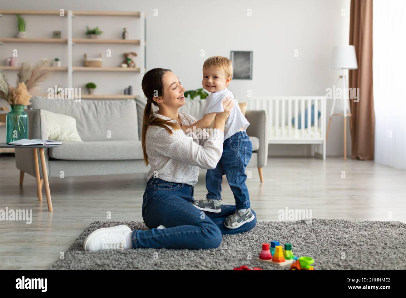 Pretty young mother enjoying time with her adorable toddler son at home ...