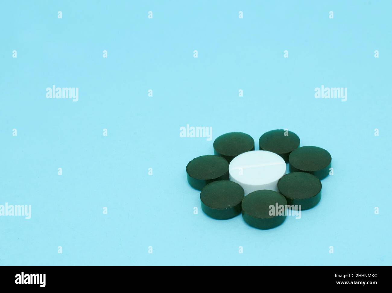 Many green tablets and one white tablet lie in the shape of a flower ...