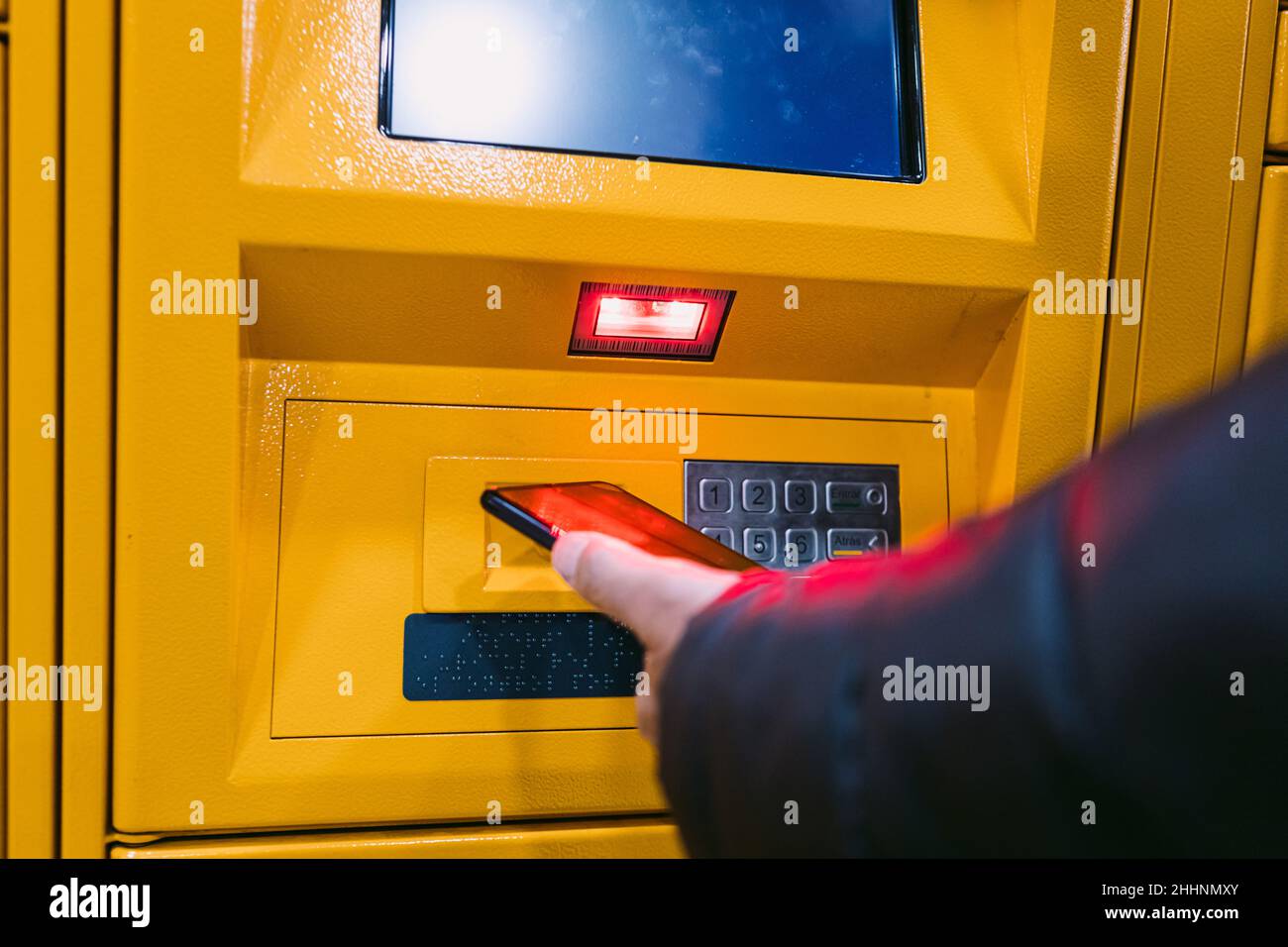 Detail of the arm of a man scanning a code on the mobile phone to pick ...