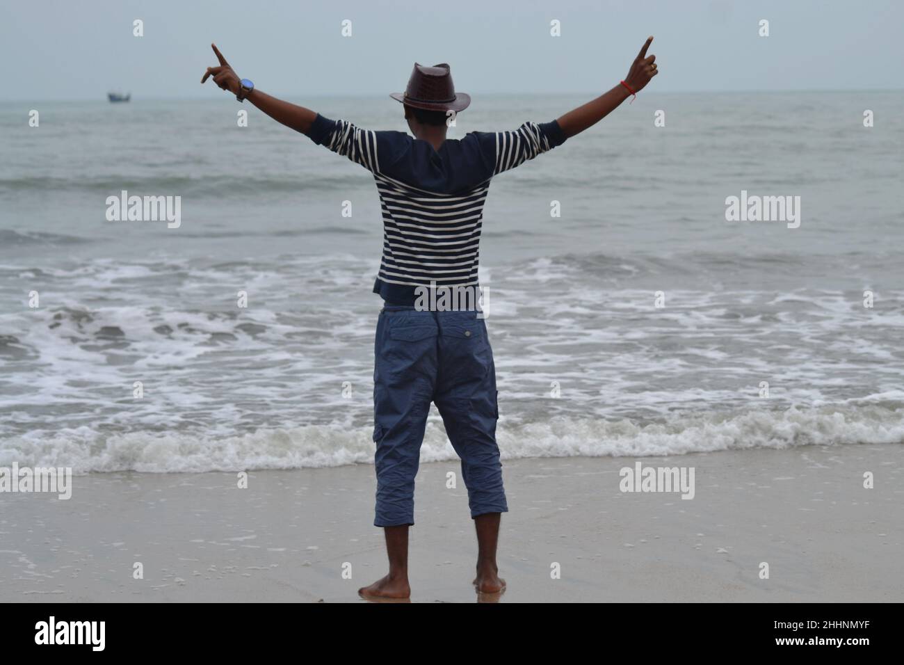 Back view of a young casual dressed man at the seaside holding both ...