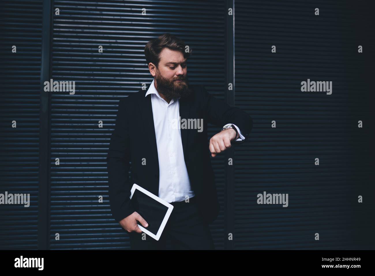 Confident businessman looking at time on wristwatch Stock Photo - Alamy