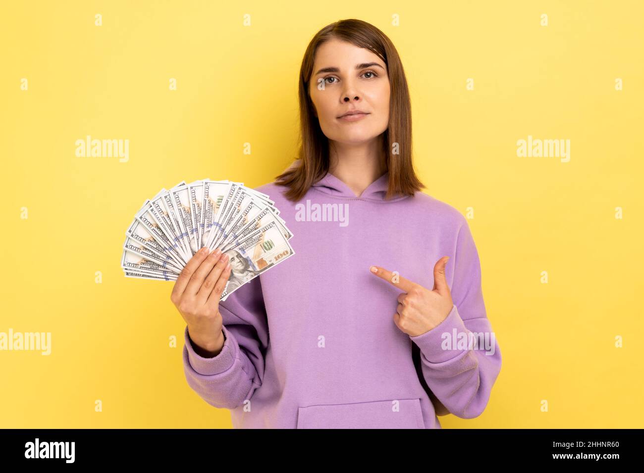 I have big money. Portrait of rich young adult woman pointing at dollar ...