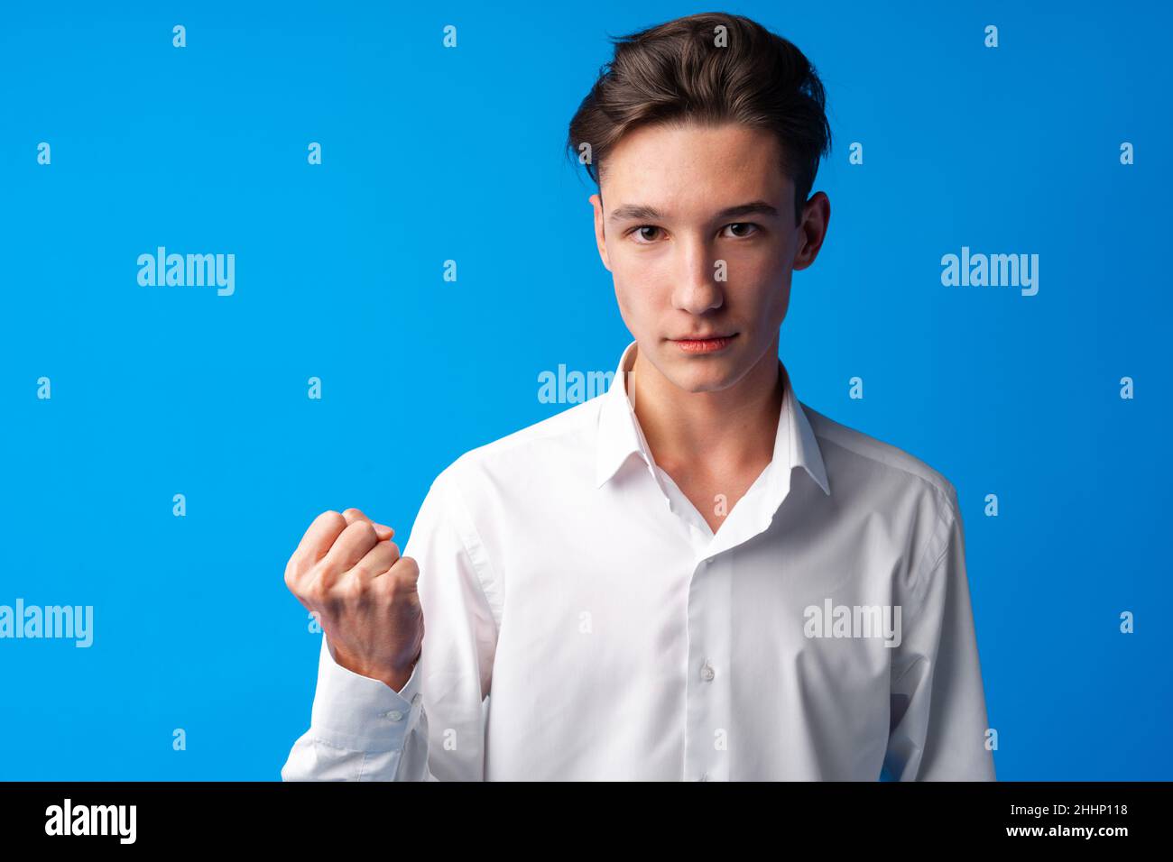 Angry stressed teen boy with clenched fist on blue background Stock ...
