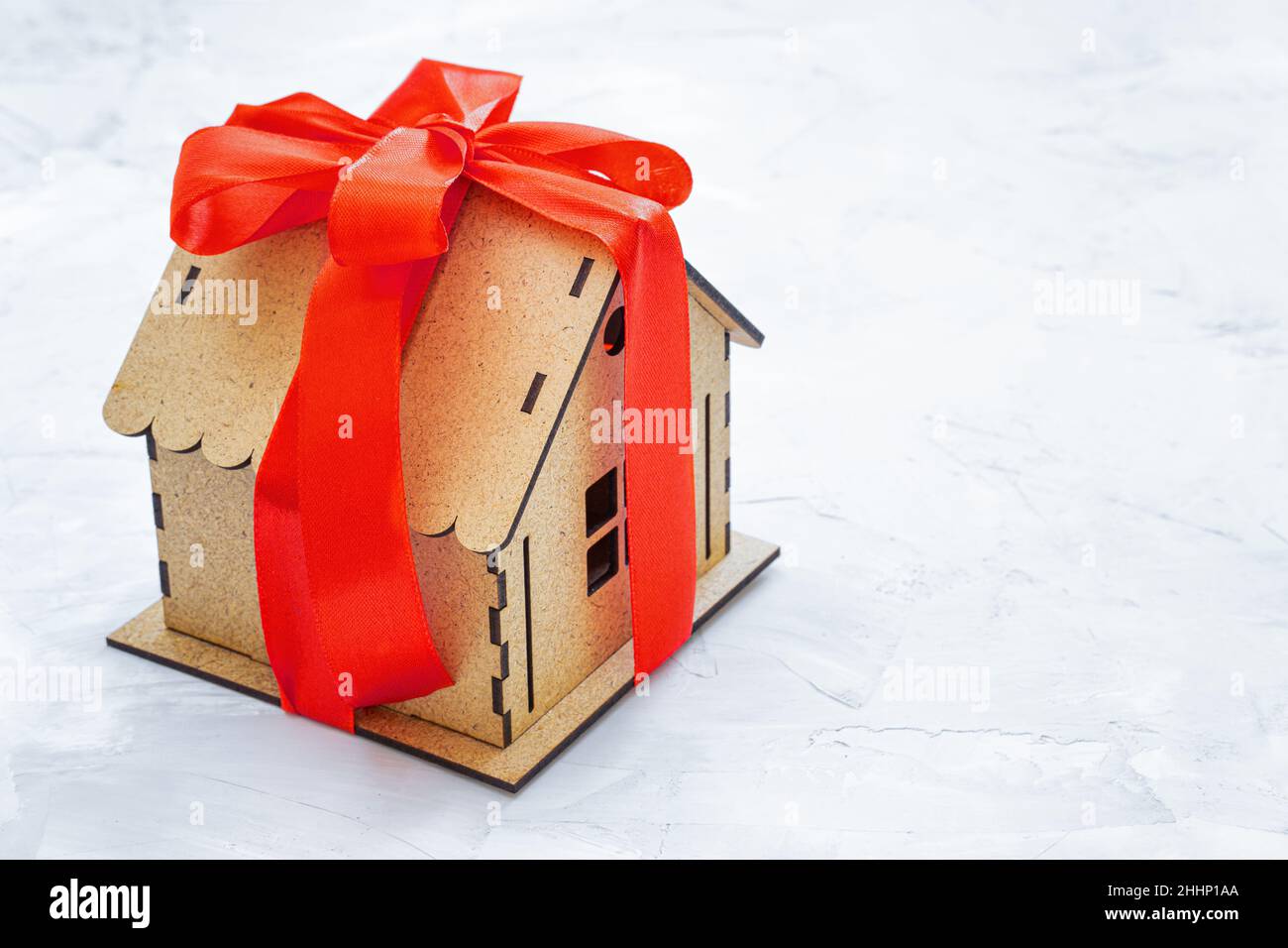 Tiny toy house decorated with a red ribbon and a bow. Home ownership ...