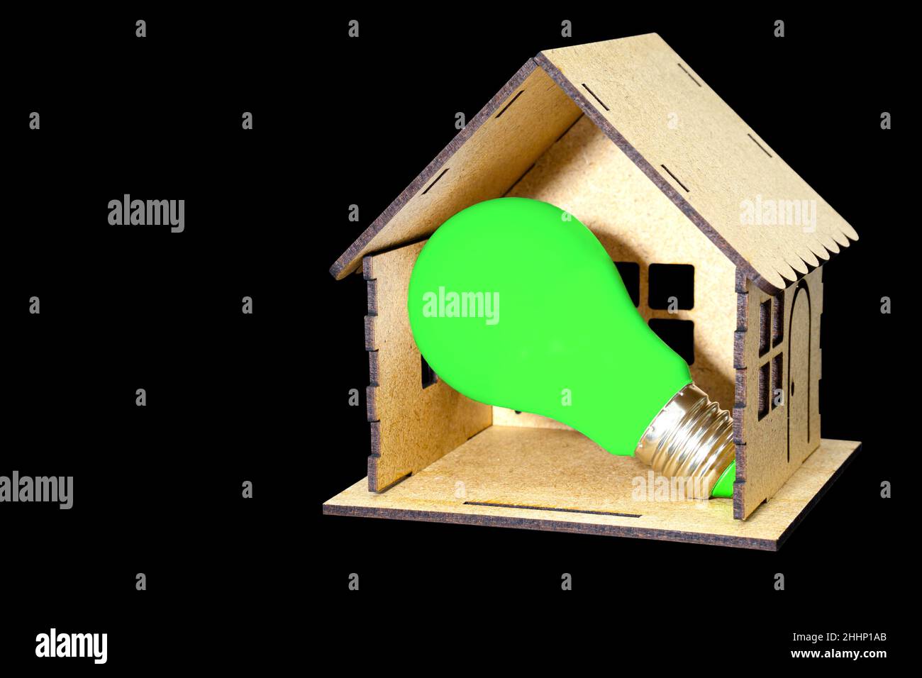 Green colored energy efficient light bulb inside a miniature wooden ...