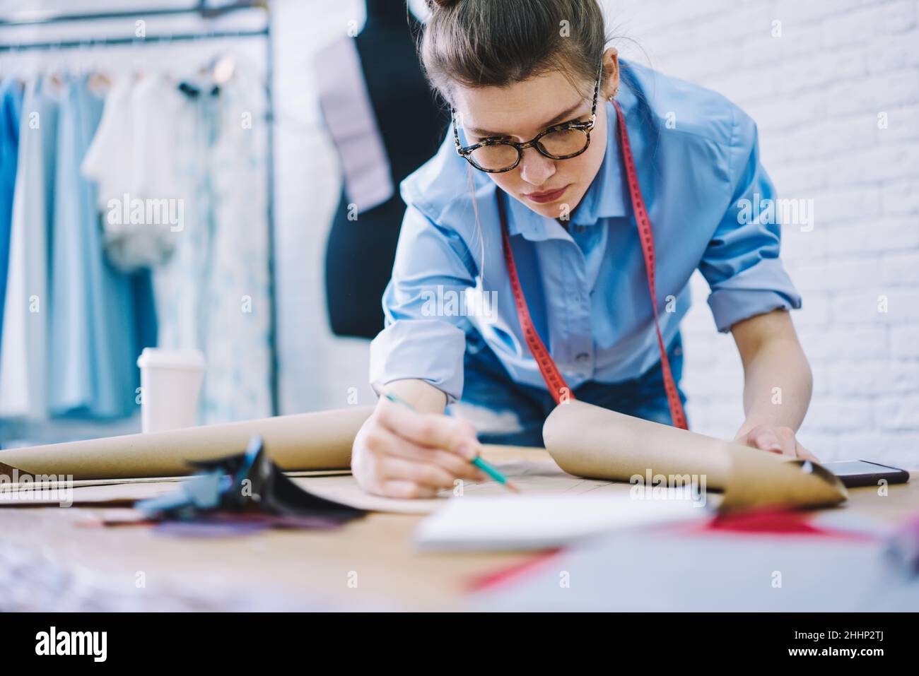 Concentrated female dressmaker drawing on paper in studio Stock Photo ...