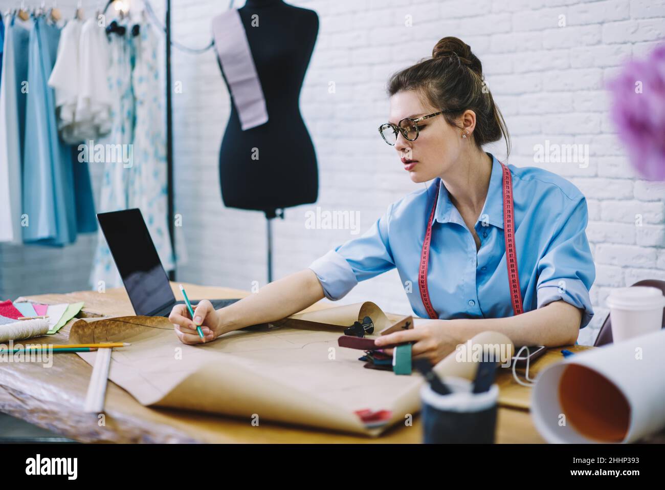 Focused dressmaker working at table in modern studio Stock Photo - Alamy