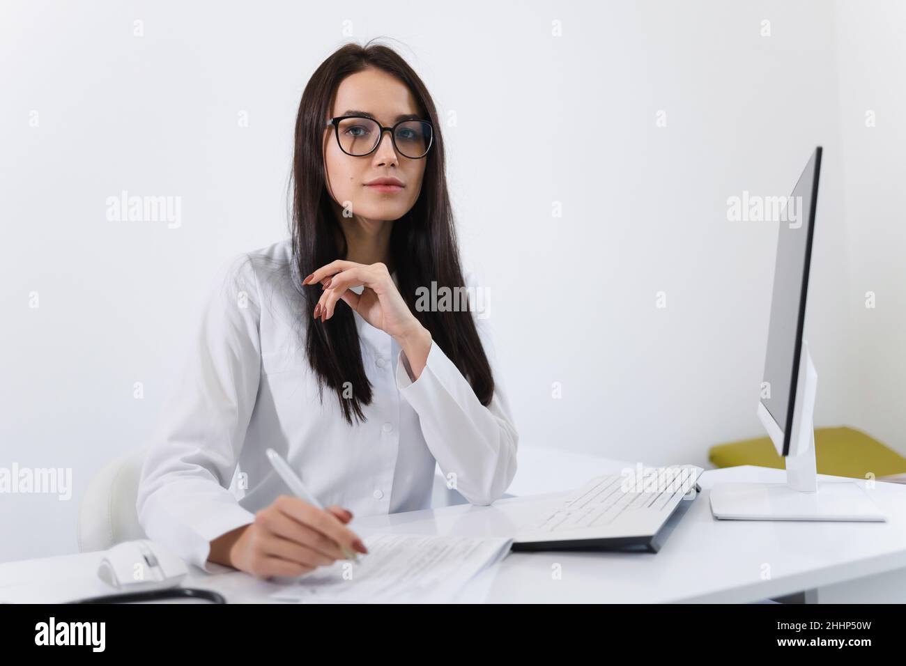 Woman healthcare worker doing some paperwork and using computer while ...