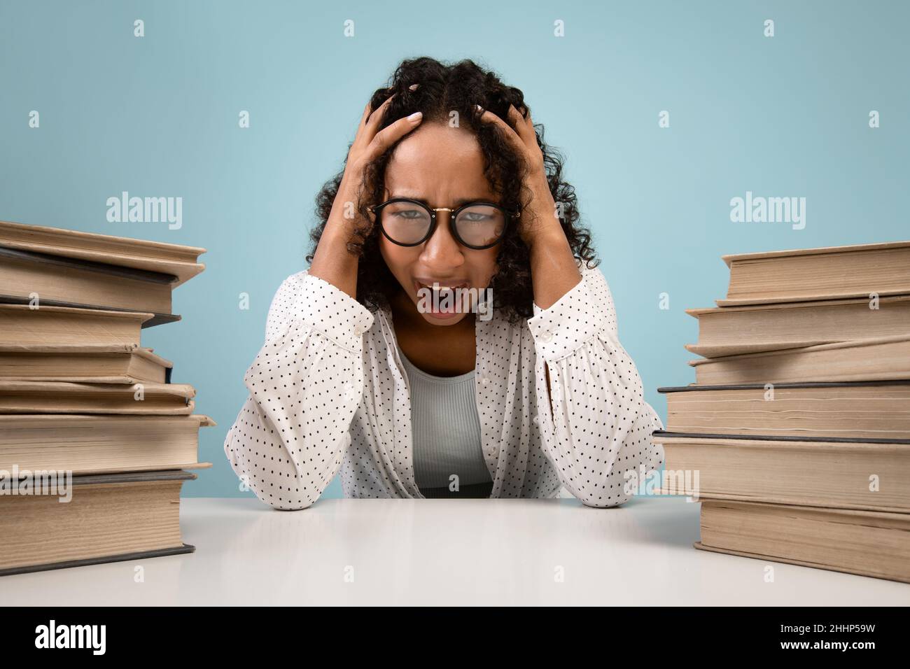 Stressed African American female student with heaps of books yelling on ...