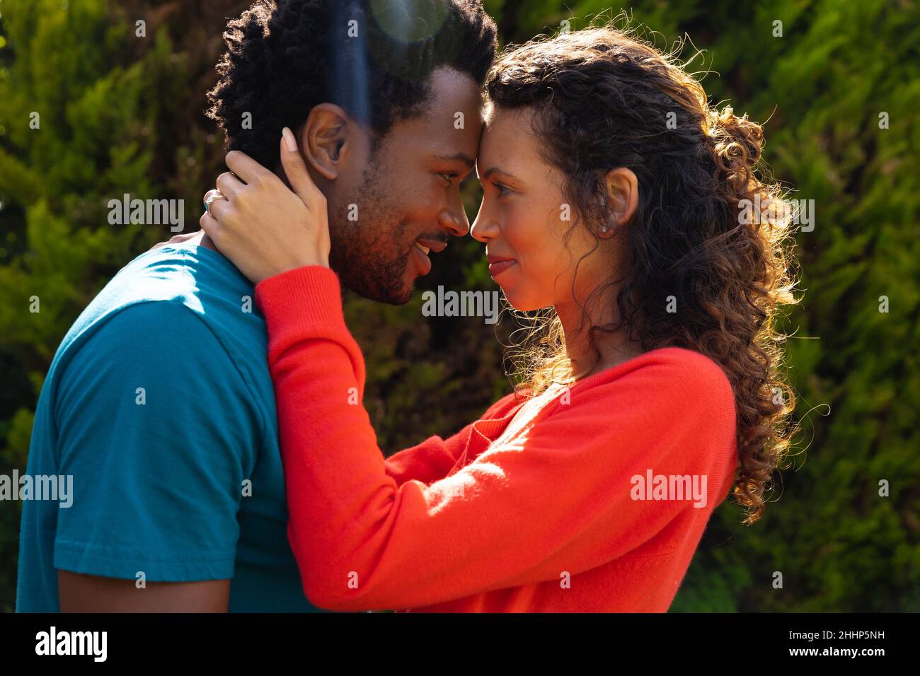 Side view of young multiracial couple romancing while touching forehead ...