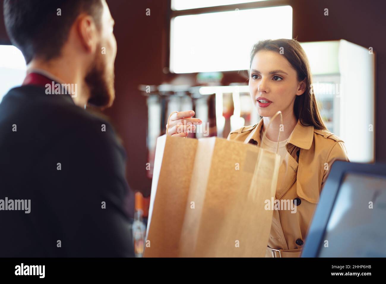 Shop assistant handling shopping bag to female customer in grocery ...
