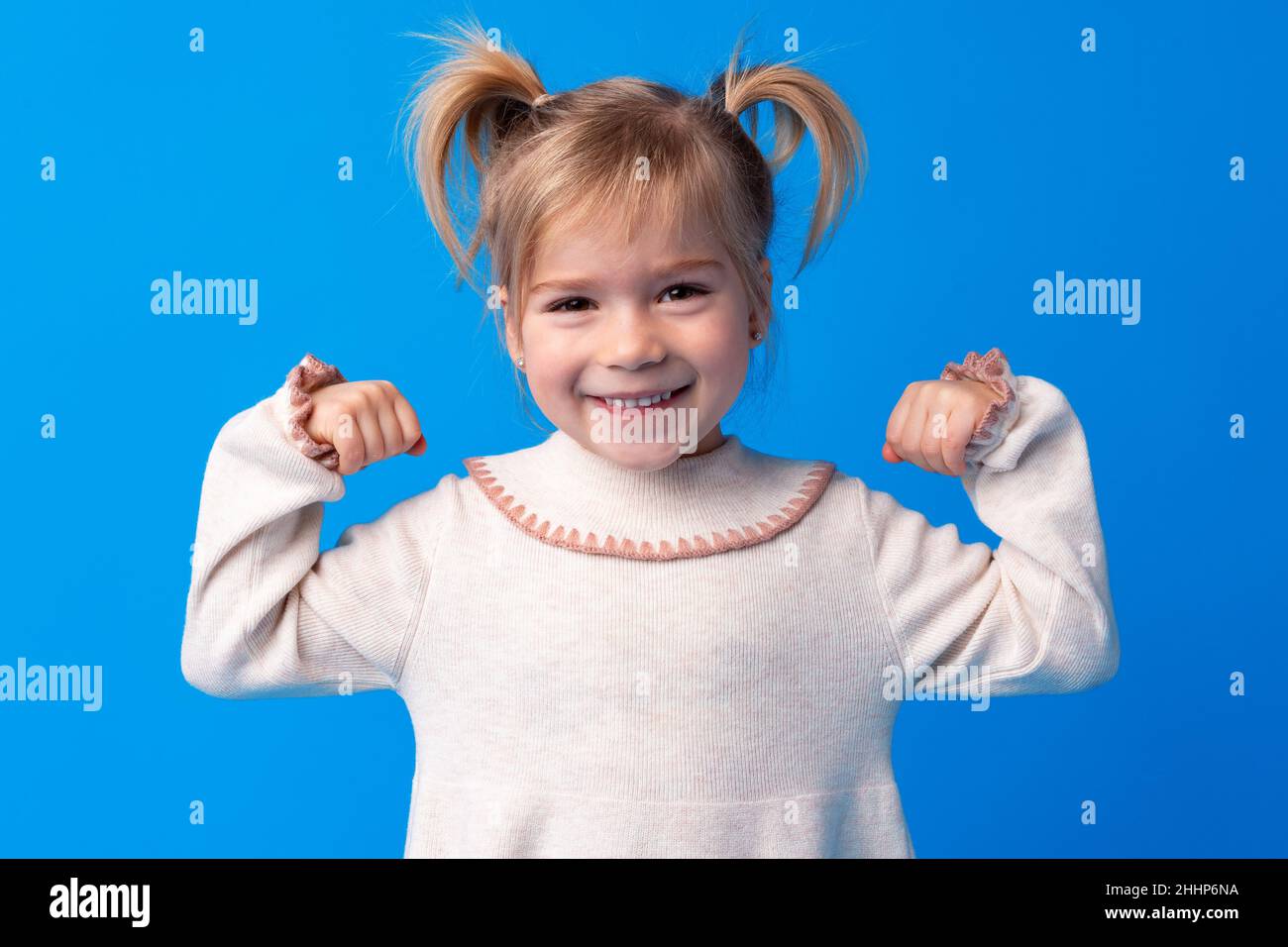 Little cute girl showing her strength against blue background Stock ...