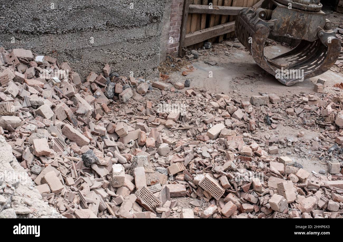 a large shovel of a digger at a construction site with a heap of broken ...