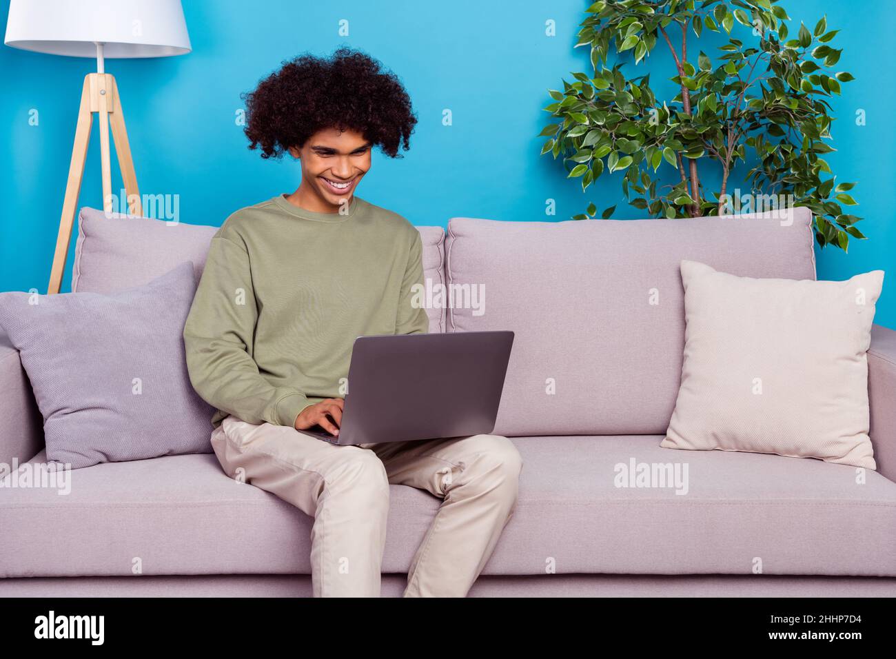 Photo of young man sit divan use laptop type chatting digital modern ...