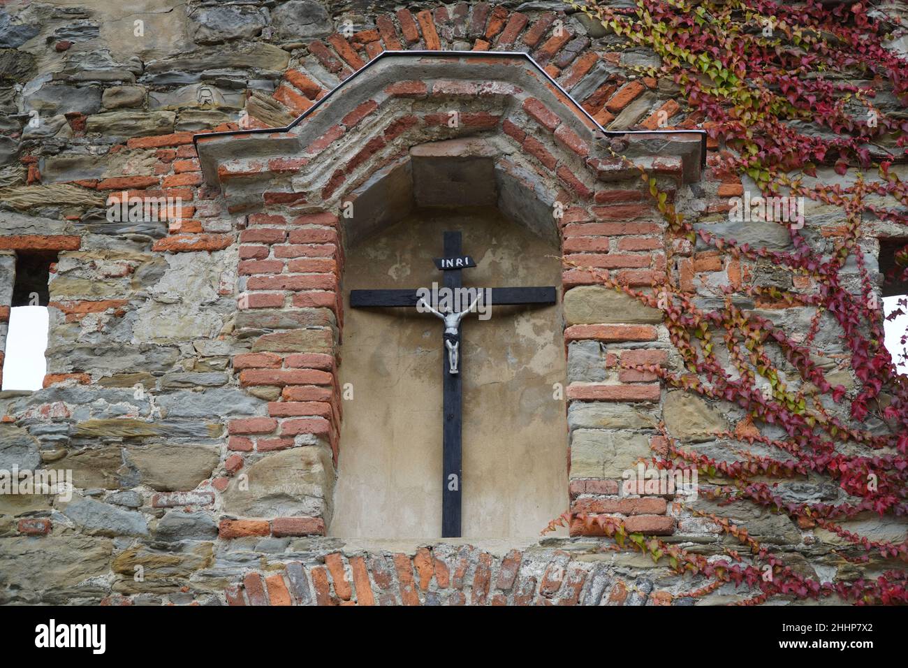 a large wooden cross hanging in the bricked up window of an old wall ...