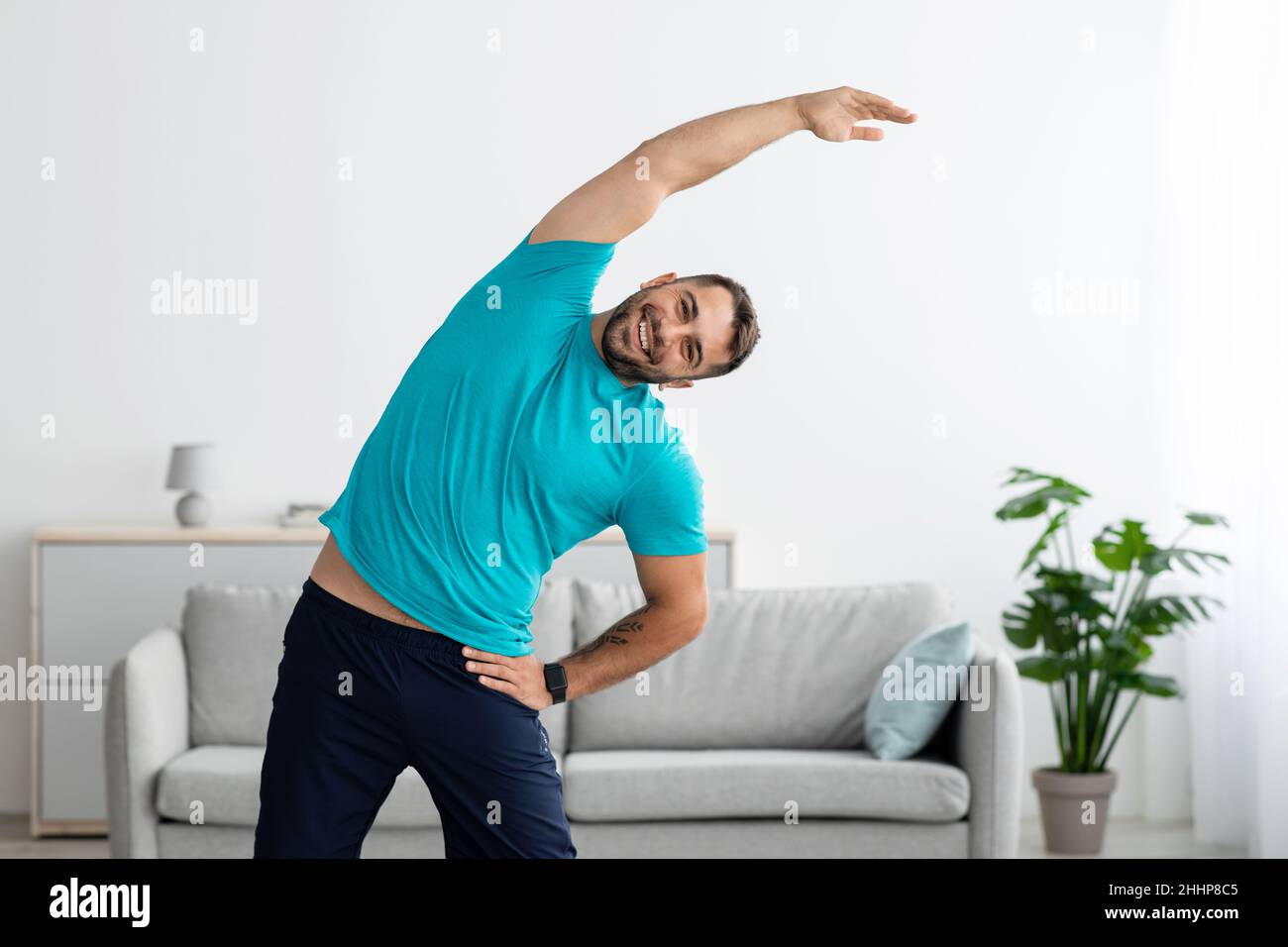 Glad happy young european muscular male doing arm exercises, stretching ...