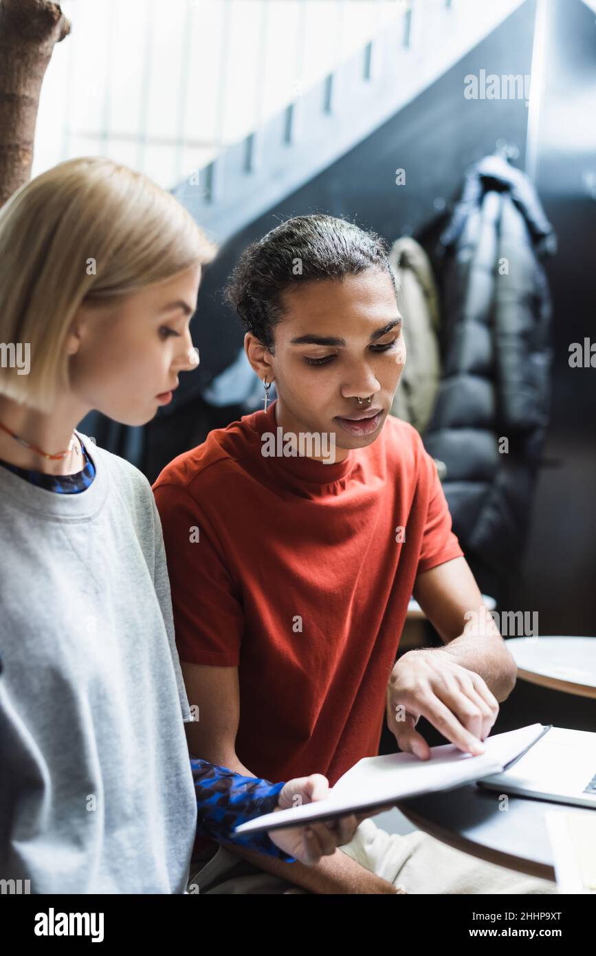 African american freelancer pointing at notebook near friend and ...