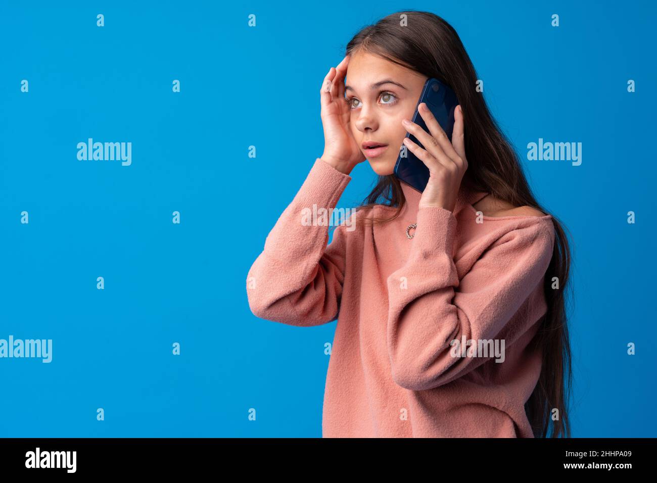 Pretty teenage girl talking on the mobile phone against blue background ...