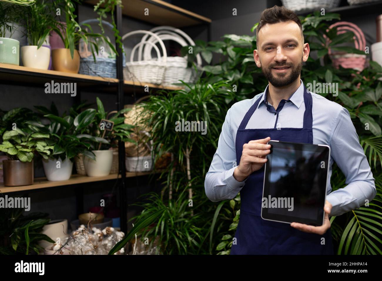 florist man demonstrates the screen of the tablet against the ...
