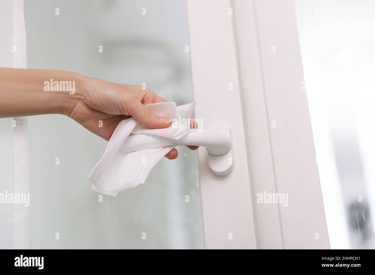 Cleaning door handles with an antiseptic wet wipe and gloves. Woman ...