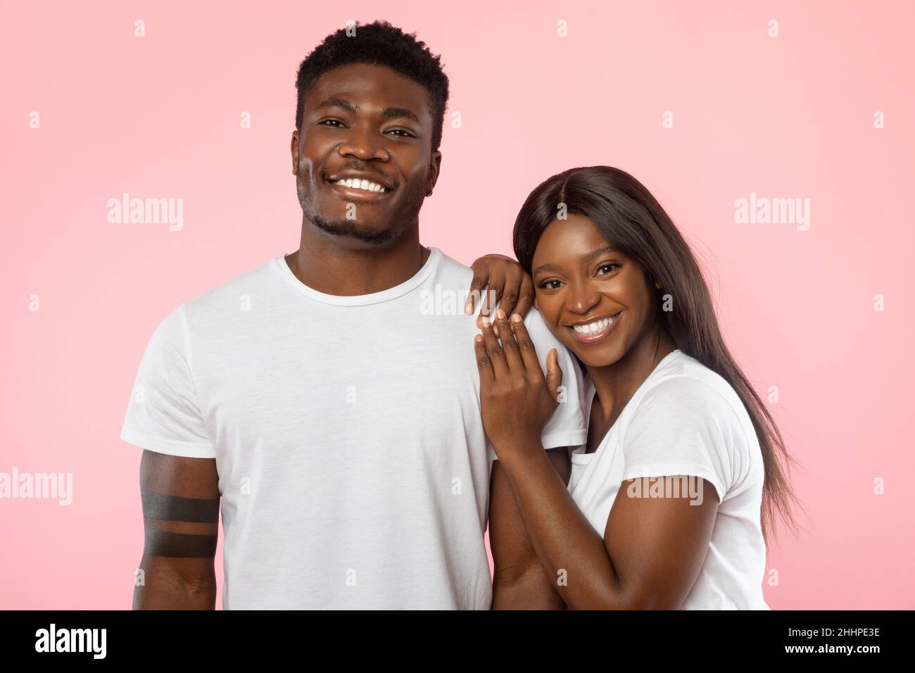 Confident couple standing and posing at pink studio background Stock ...
