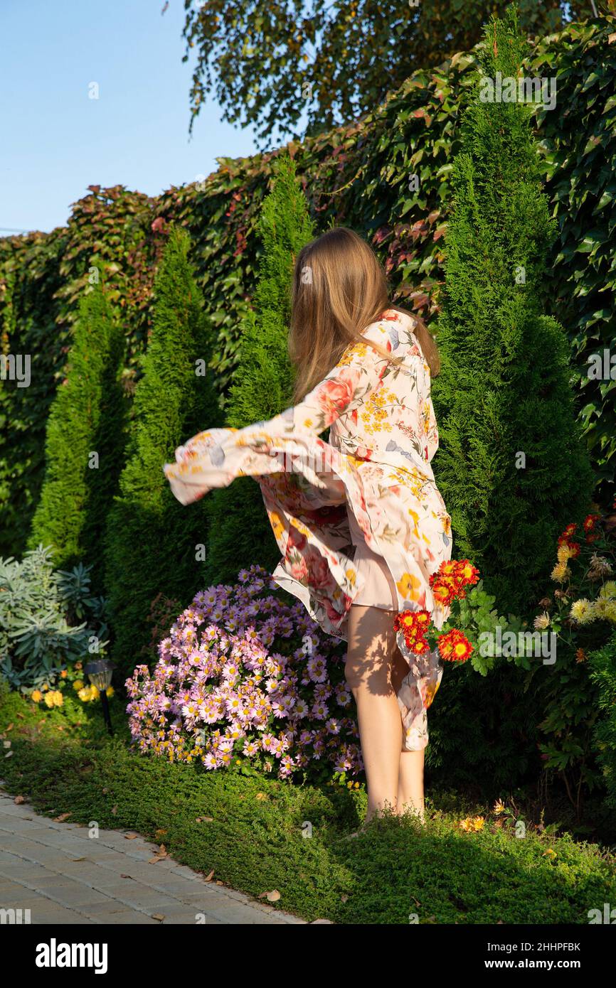 Standing young woman with white skin with greenery behind in floral ...