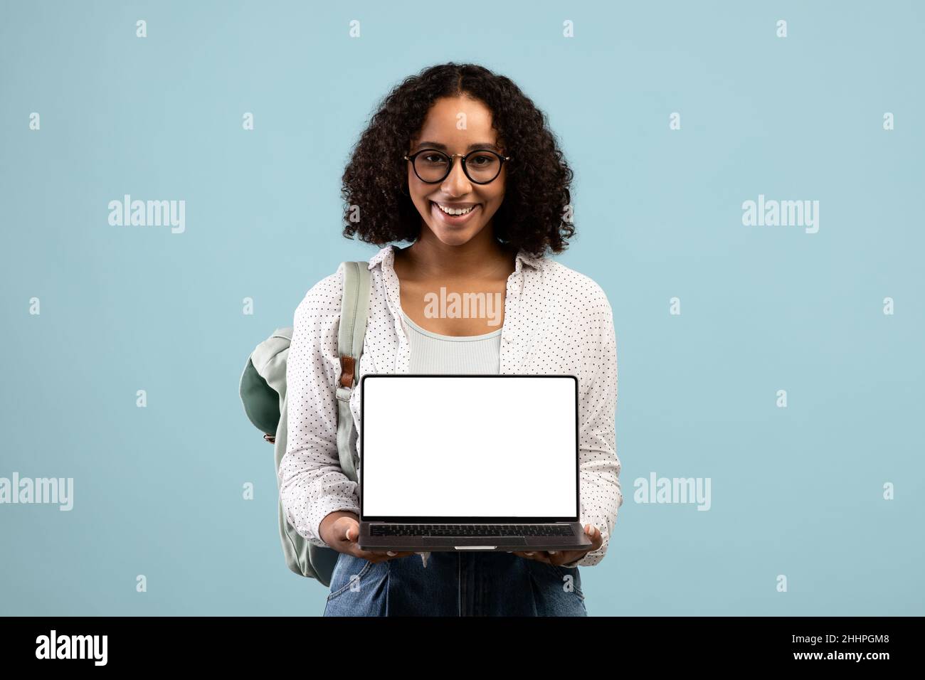 Portrait of young black female student holding laptop with blank screen ...