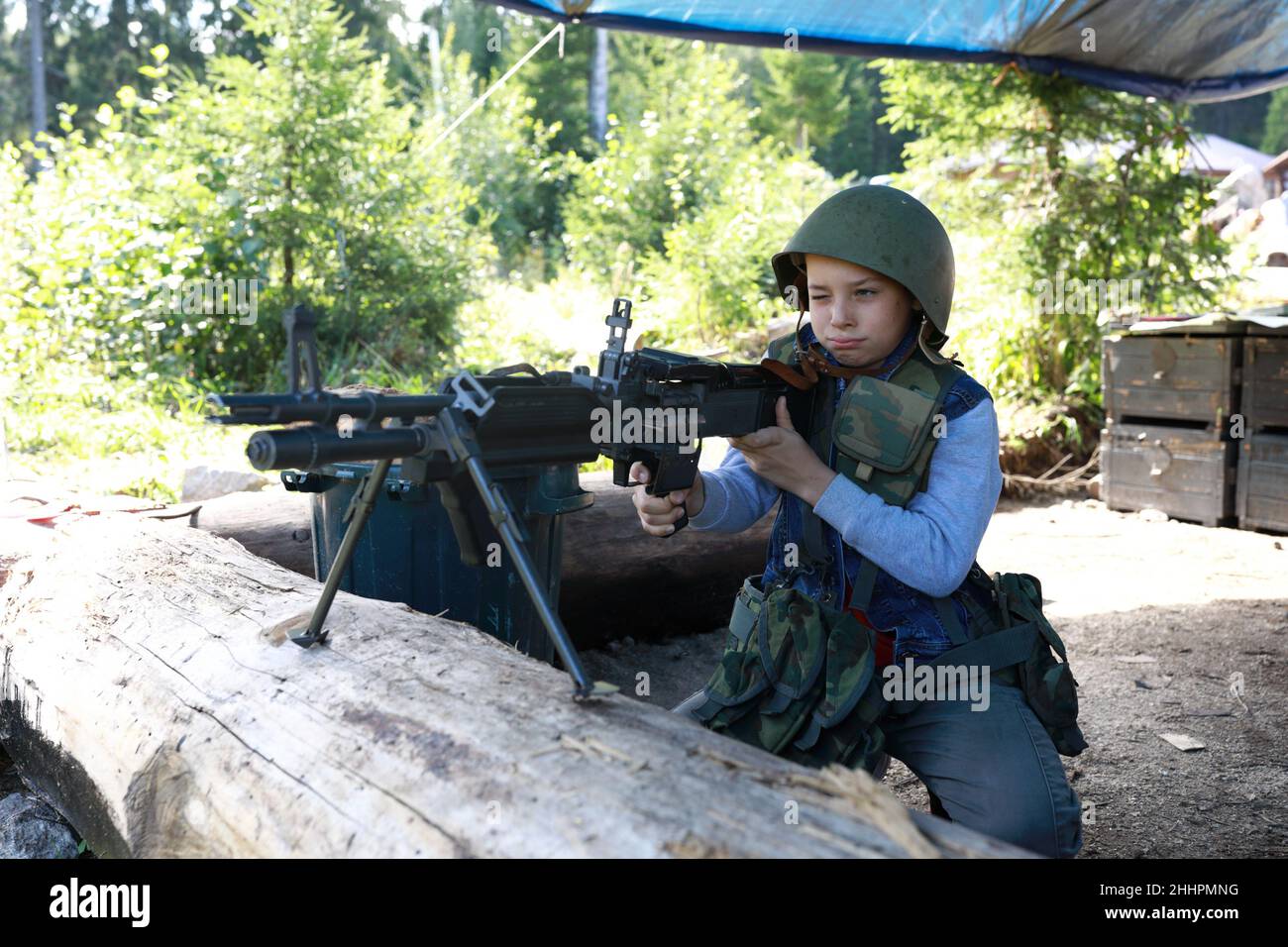 Kid in military helmet aims with machine gun in park Stock Photo - Alamy