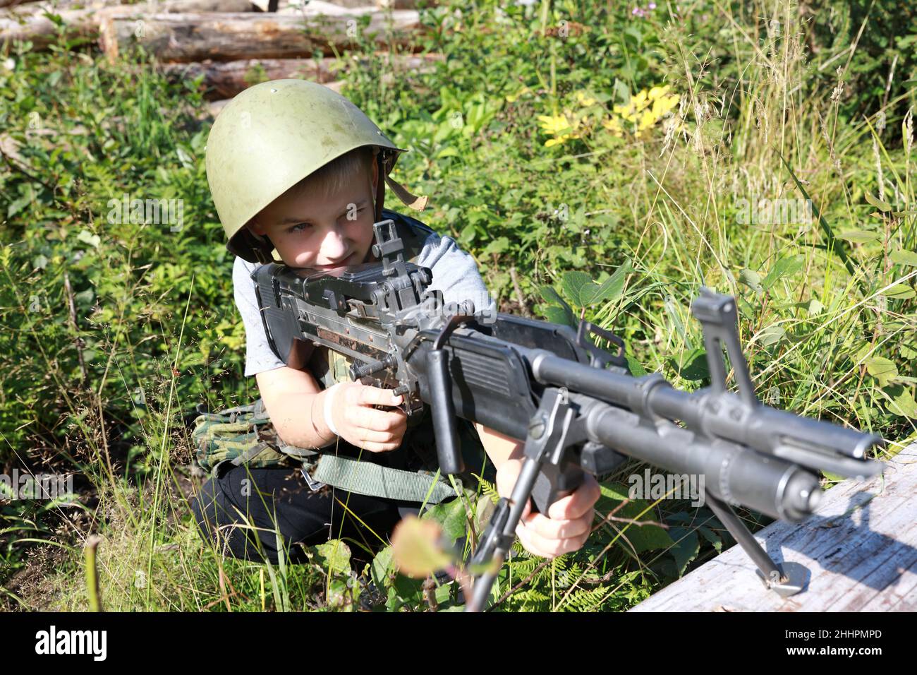 Child in military helmet aims with machine gun in park Stock Photo - Alamy