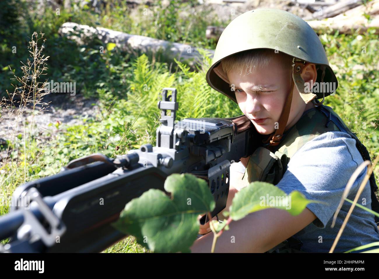 Kid in military helmet with machine gun in park Stock Photo - Alamy