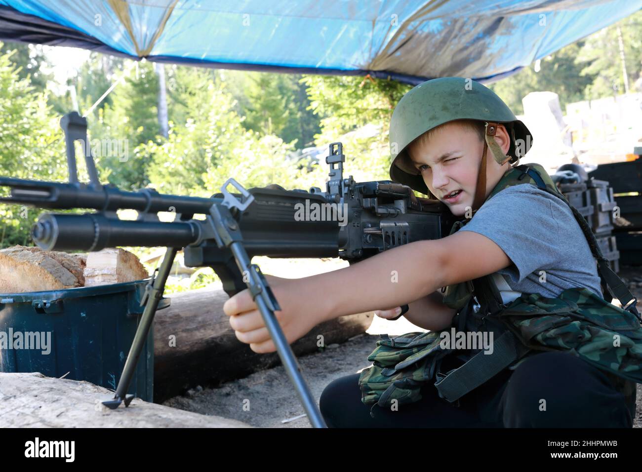 Boy in military helmet with machine gun in park Stock Photo - Alamy