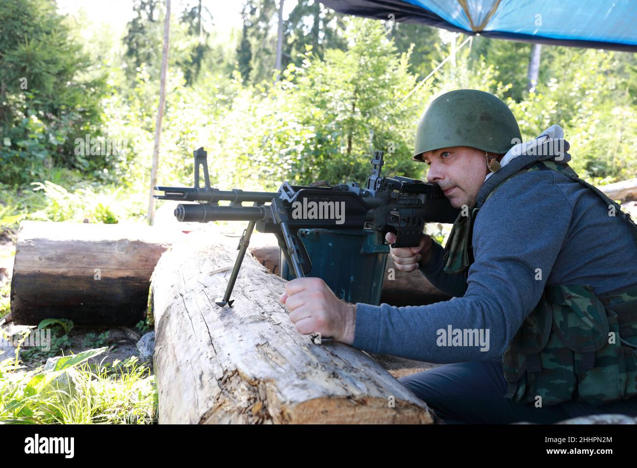 Man in military helmet aims with machine gun in park Stock Photo - Alamy