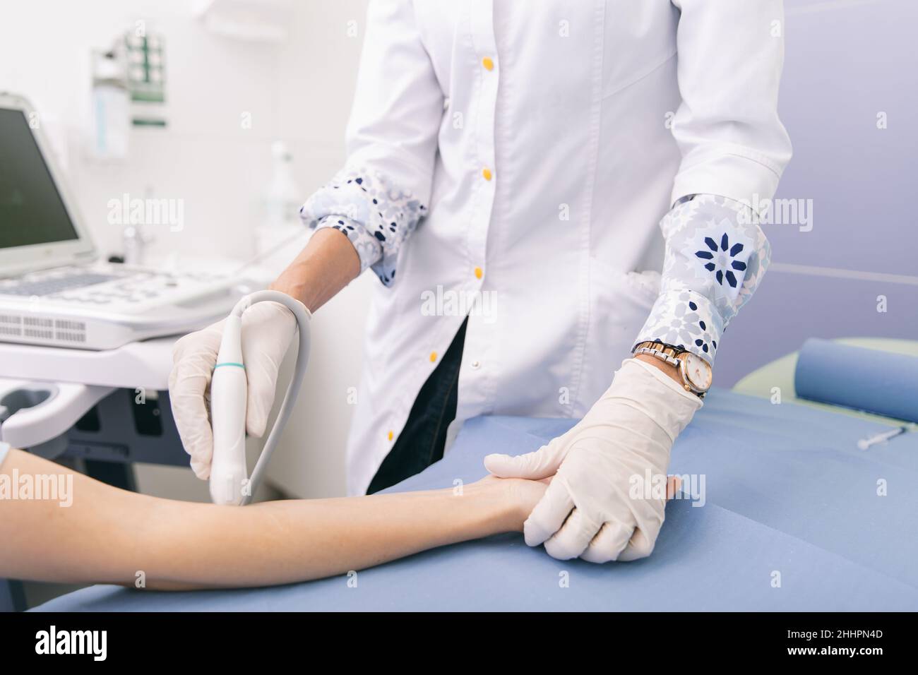 Doctor doing the ultrasound on the hand close up. Doctor demonstrates ...