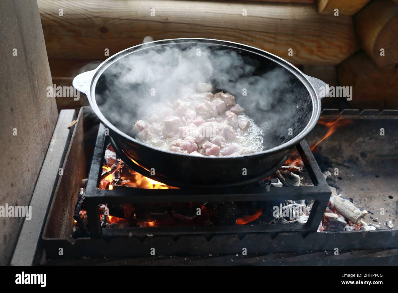 Frying meat in cauldron on fire in gazebo for pilaf Stock Photo - Alamy