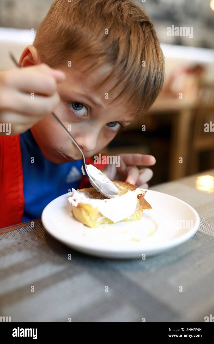 Boy eating cheesecake with sour cream in restaurant Stock Photo - Alamy