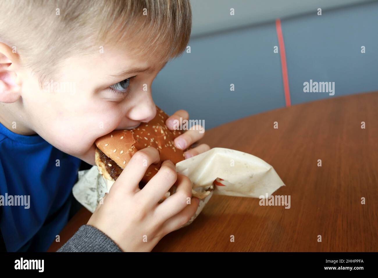 Hungry kid eating burger in a restaurant Stock Photo - Alamy
