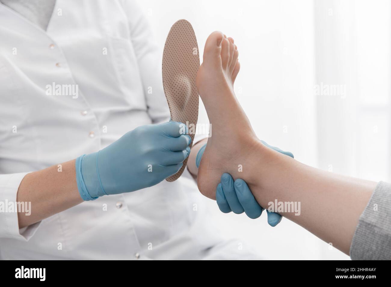 Orthopedic insole on a white background. Hands in rubber gloves hold an ...