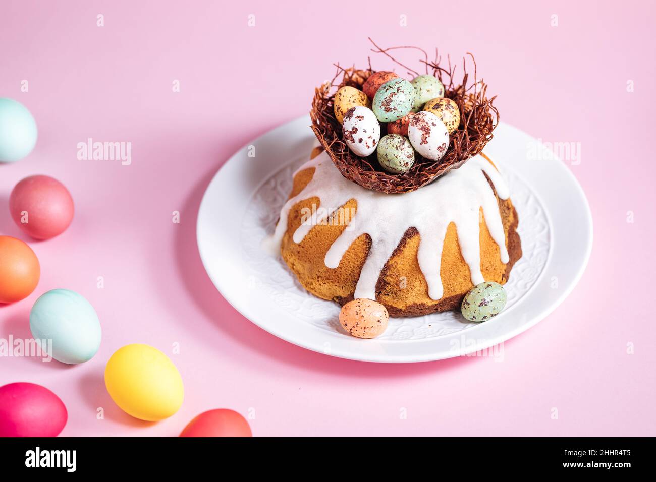 Easter cake with colorful eggs in a chocolate nest on pink background ...