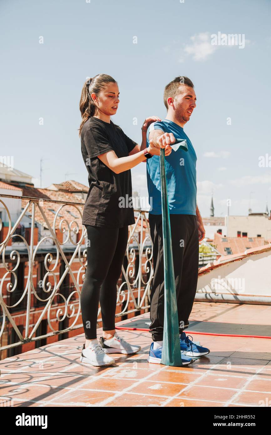 A couple doing training with rubber resistance band on their fooftop ...